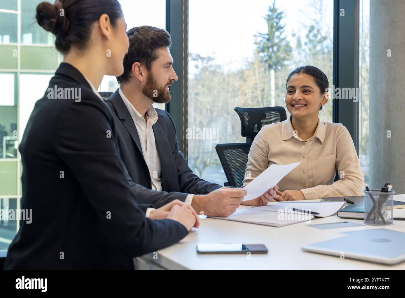 Job interview scene with young woman engaged with two professionals in ...