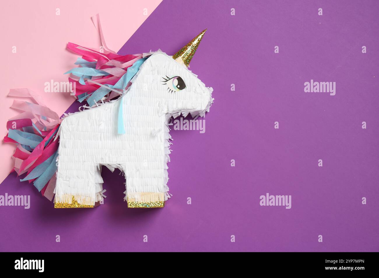 Bright pinata in shape of unicorn on color background, top view. Space ...
