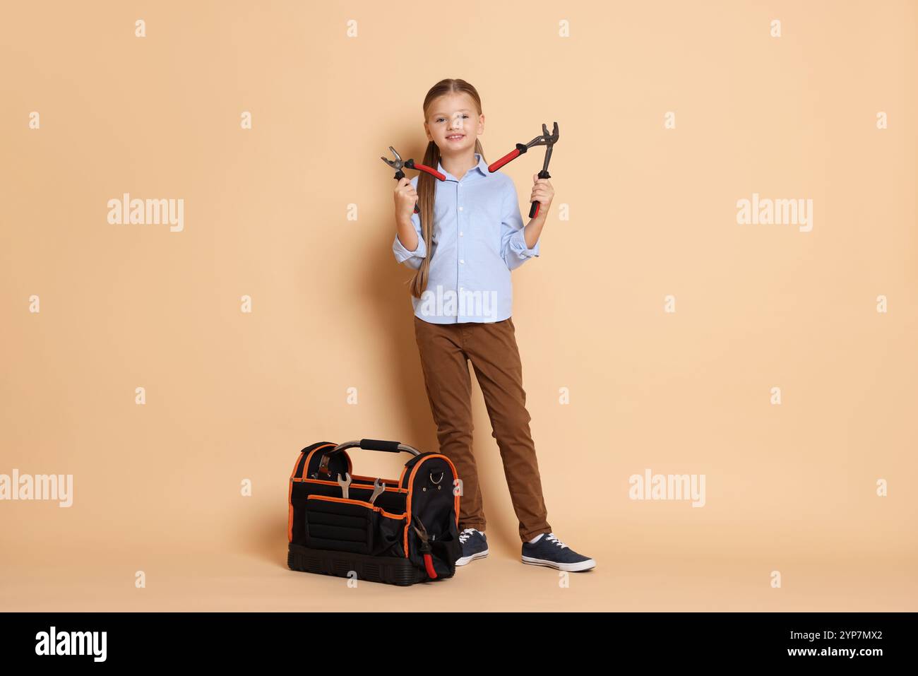 Little girl with tools on beige background. Dreaming about future ...
