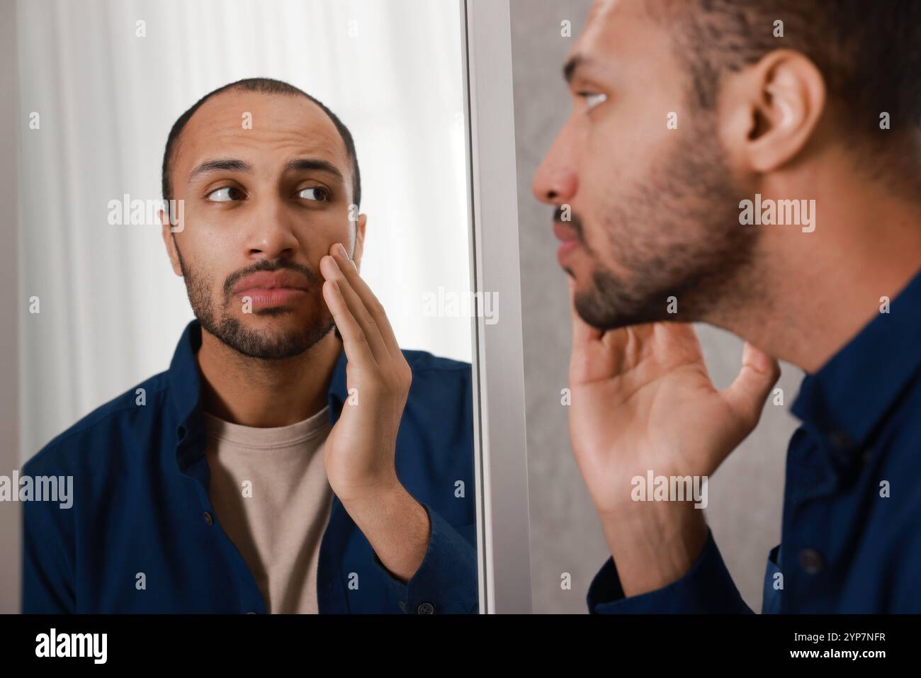 Worried man looking at mirror at home Stock Photo - Alamy