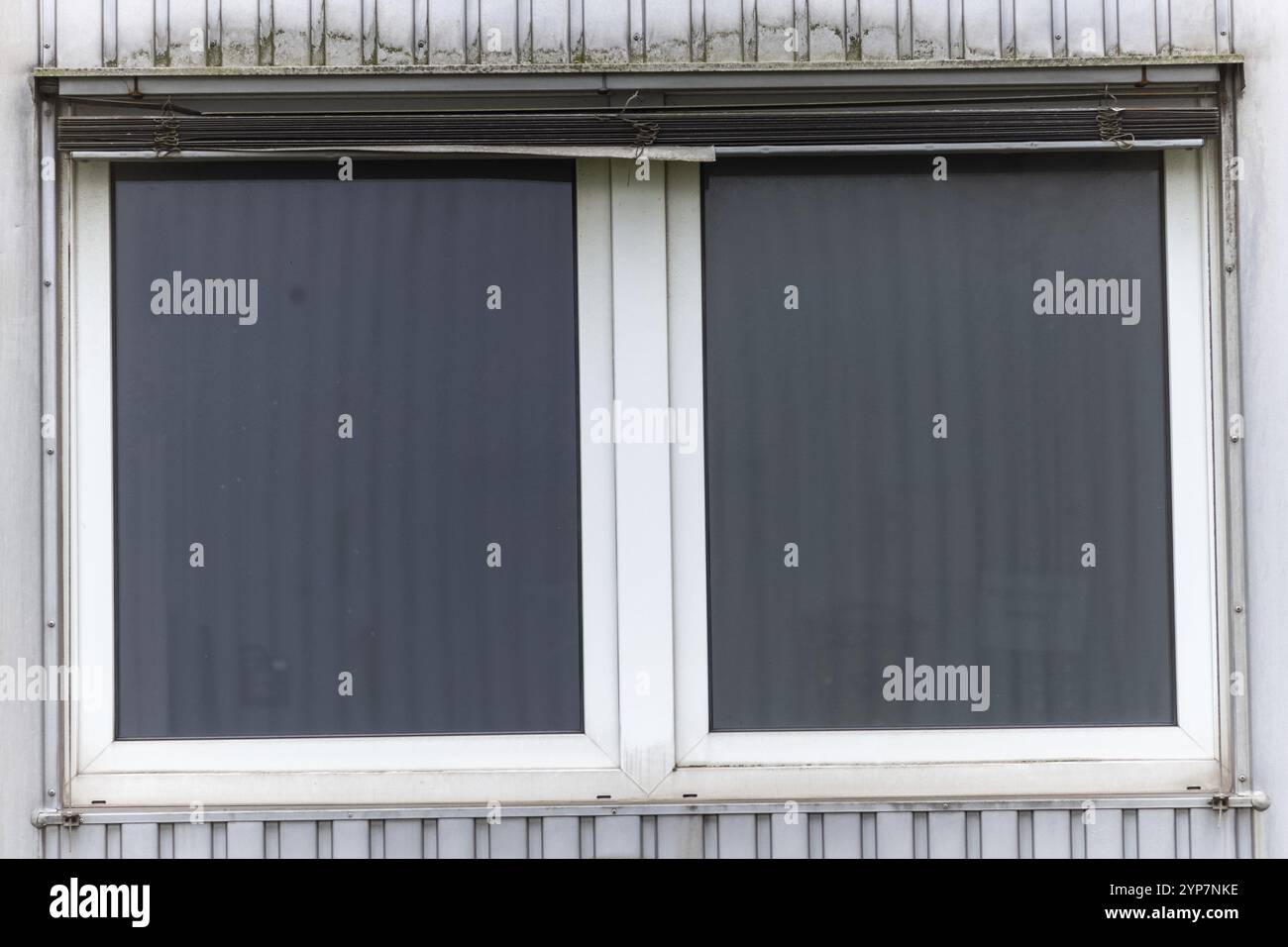 Close-up of a closed window with shades on an industrial metal building ...