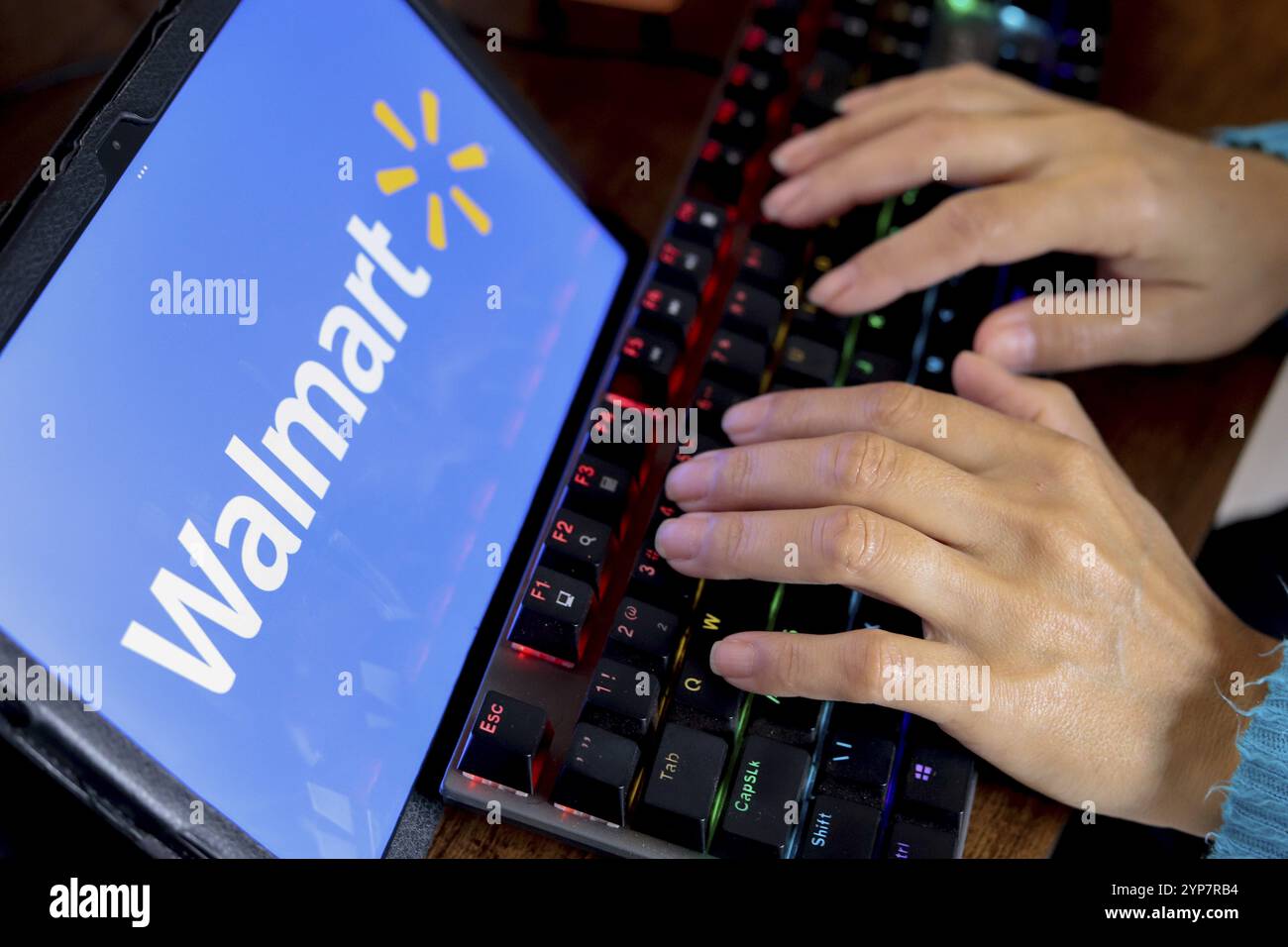 In this photo illustration, a person typing and next to the Walmart ...