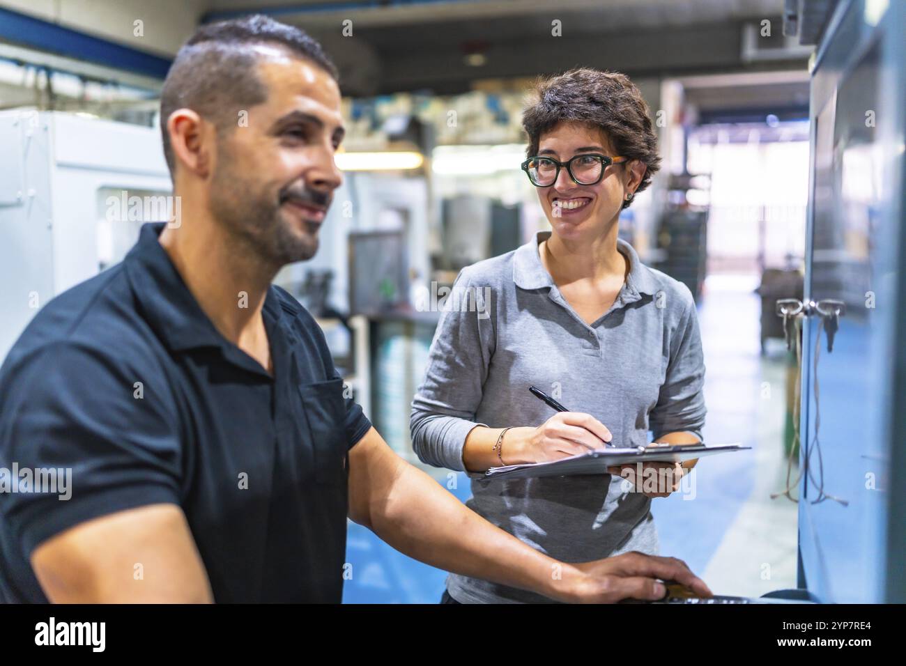 Male manual worker talking with female manager while using computer in ...