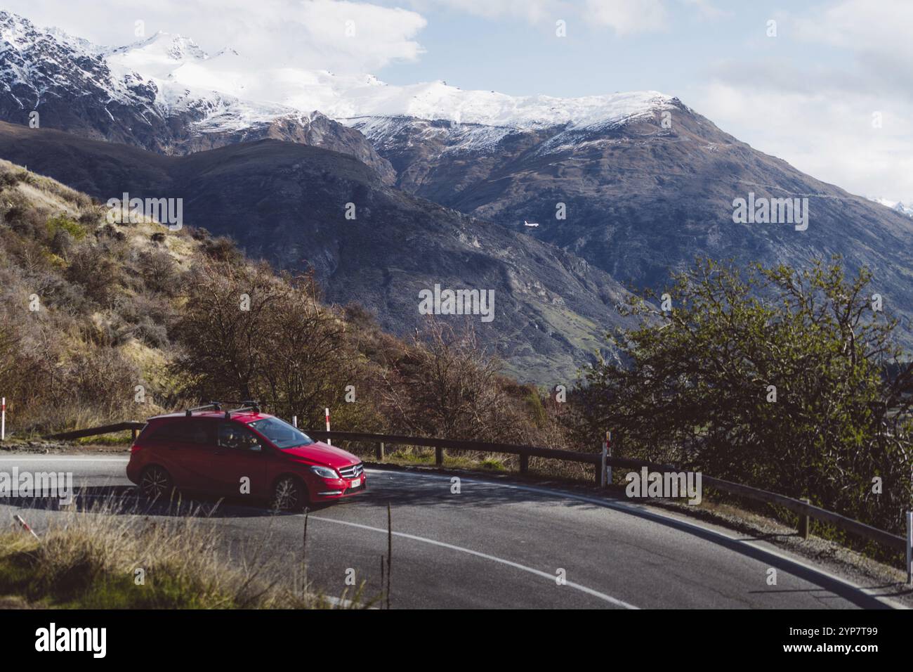 A red car driving on a winding mountain road in fine weather ...