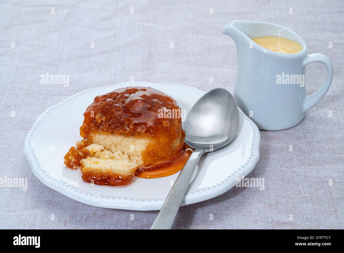 Serving of syrup sponge pudding with a jug of custard Stock Photo - Alamy