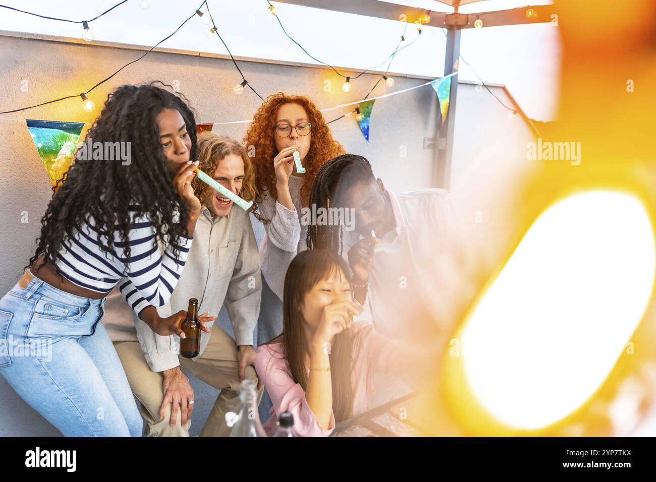 Multiracial millennial friends blowing streamers while taking selfie ...