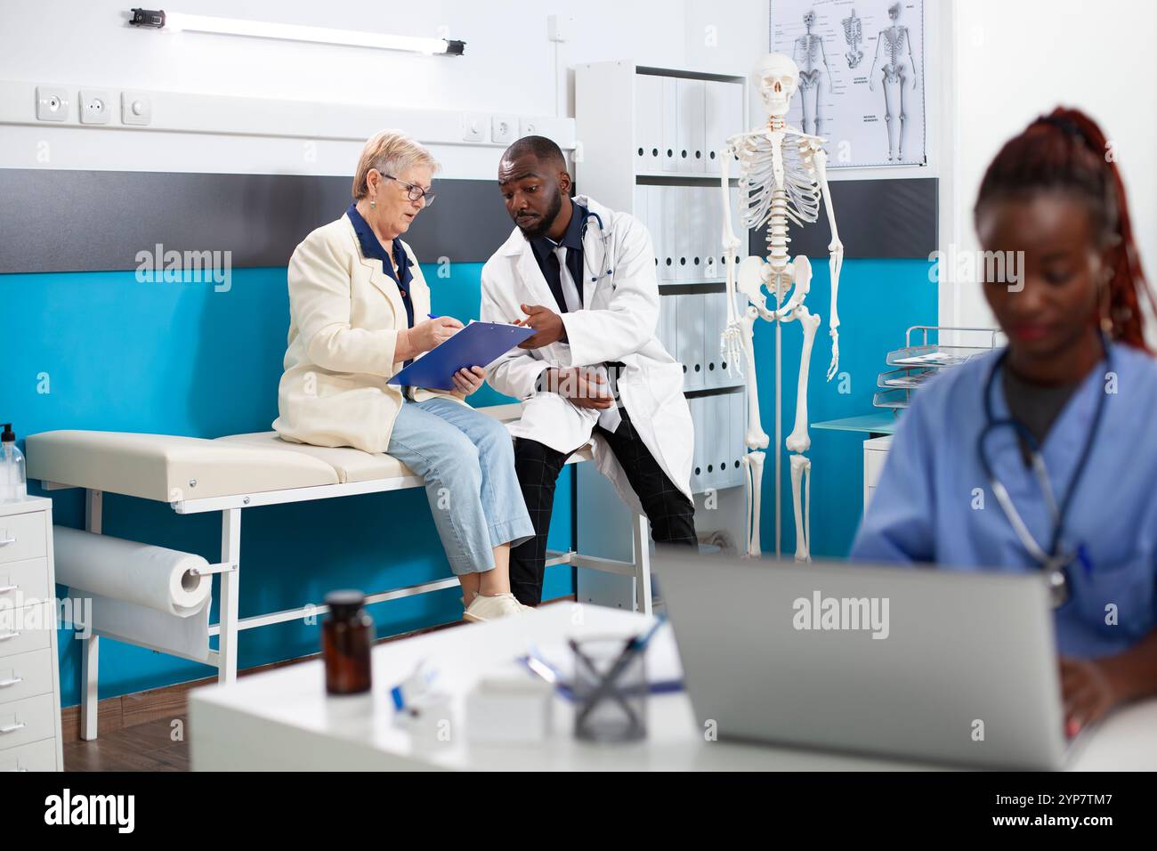 African american doctor and white old woman seated on hospital bed ...