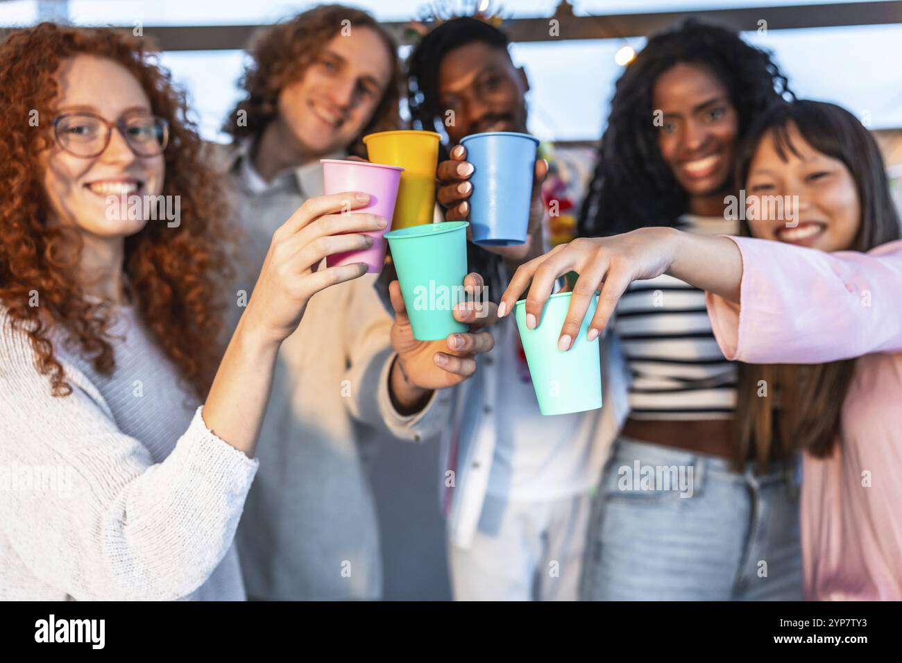 Frontal view of a group of young happy multi-ethnic friends toasting at ...