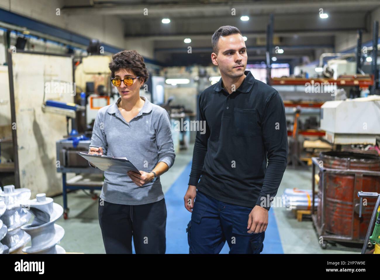 Female manager and male manual worker inspecting a cnc factory walking ...
