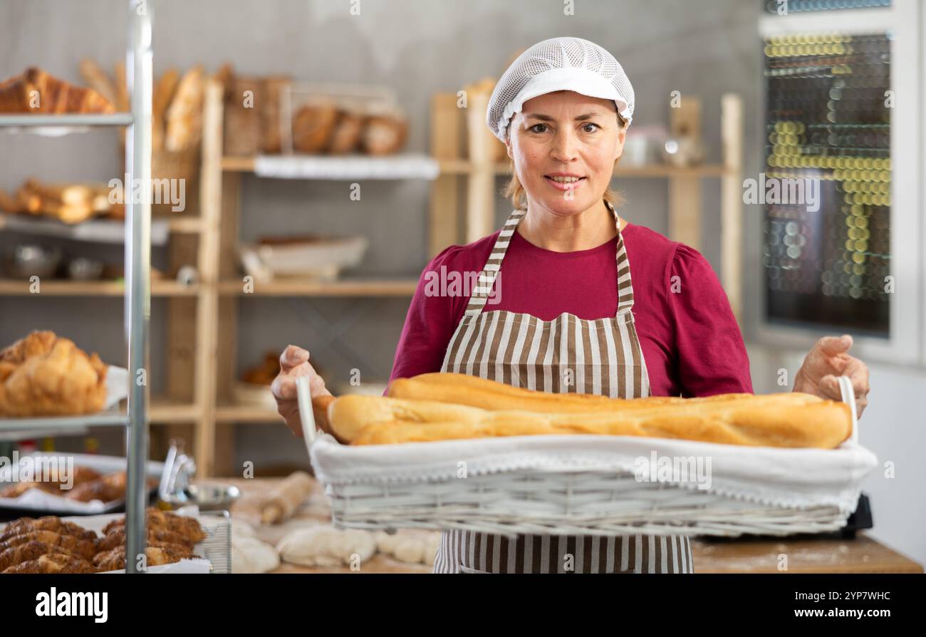 Adult female baker with basket of baguettes Stock Photo - Alamy