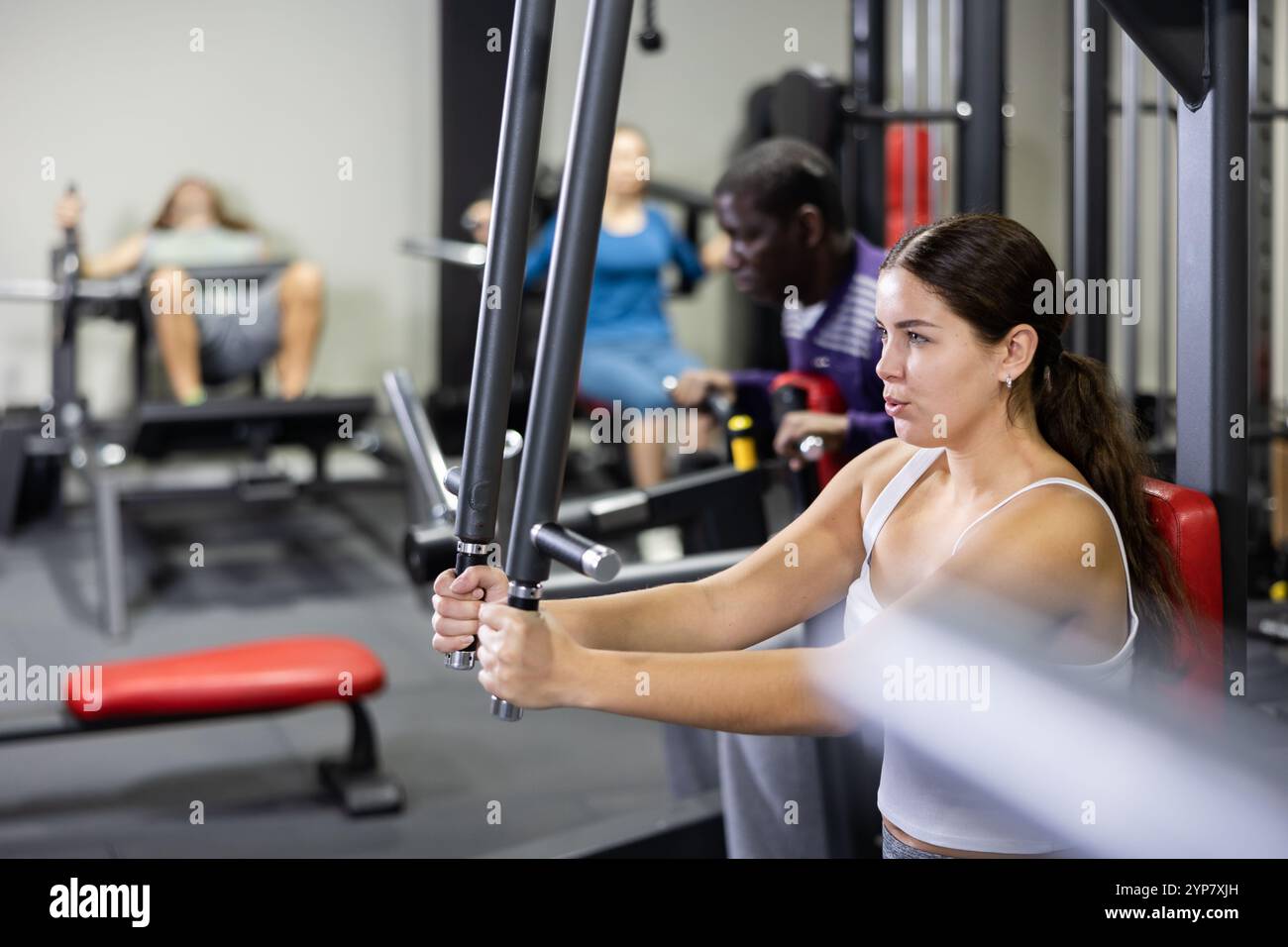 Sporty woman works on special simulator for development of pectoral ...