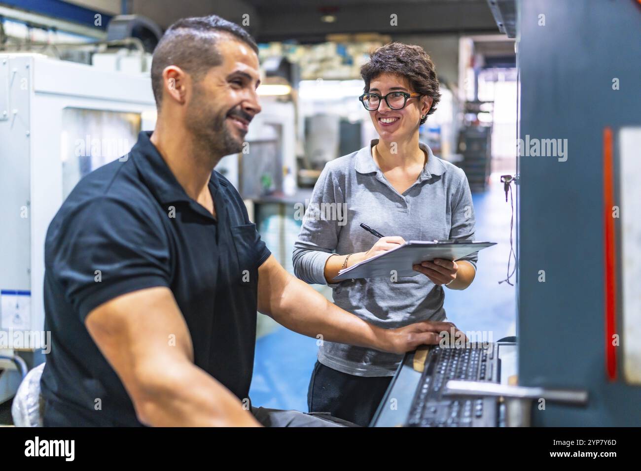 Manager and worker talking while working using computer in a cnc metal ...