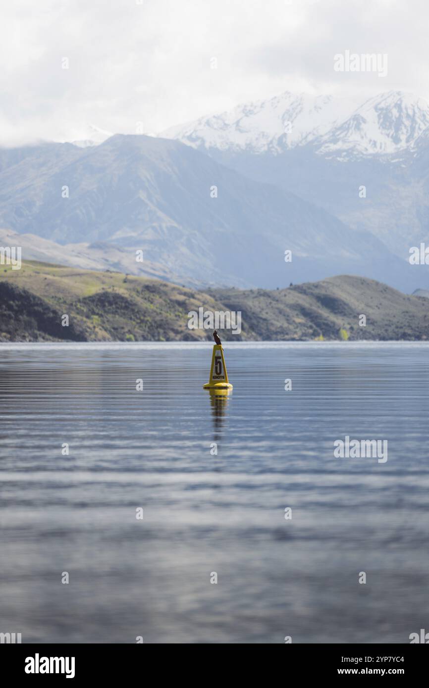 Buoy in a calm lake with mountain scenery and clouds in the background ...