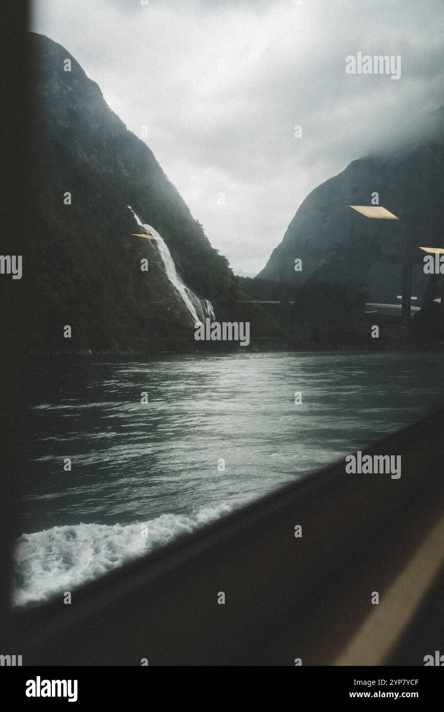 View through a window of a waterfall surrounded by misty mountains ...