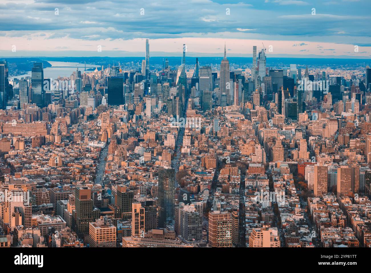 An expansive aerial view of Manhattan’s dense cityscape at sunset ...