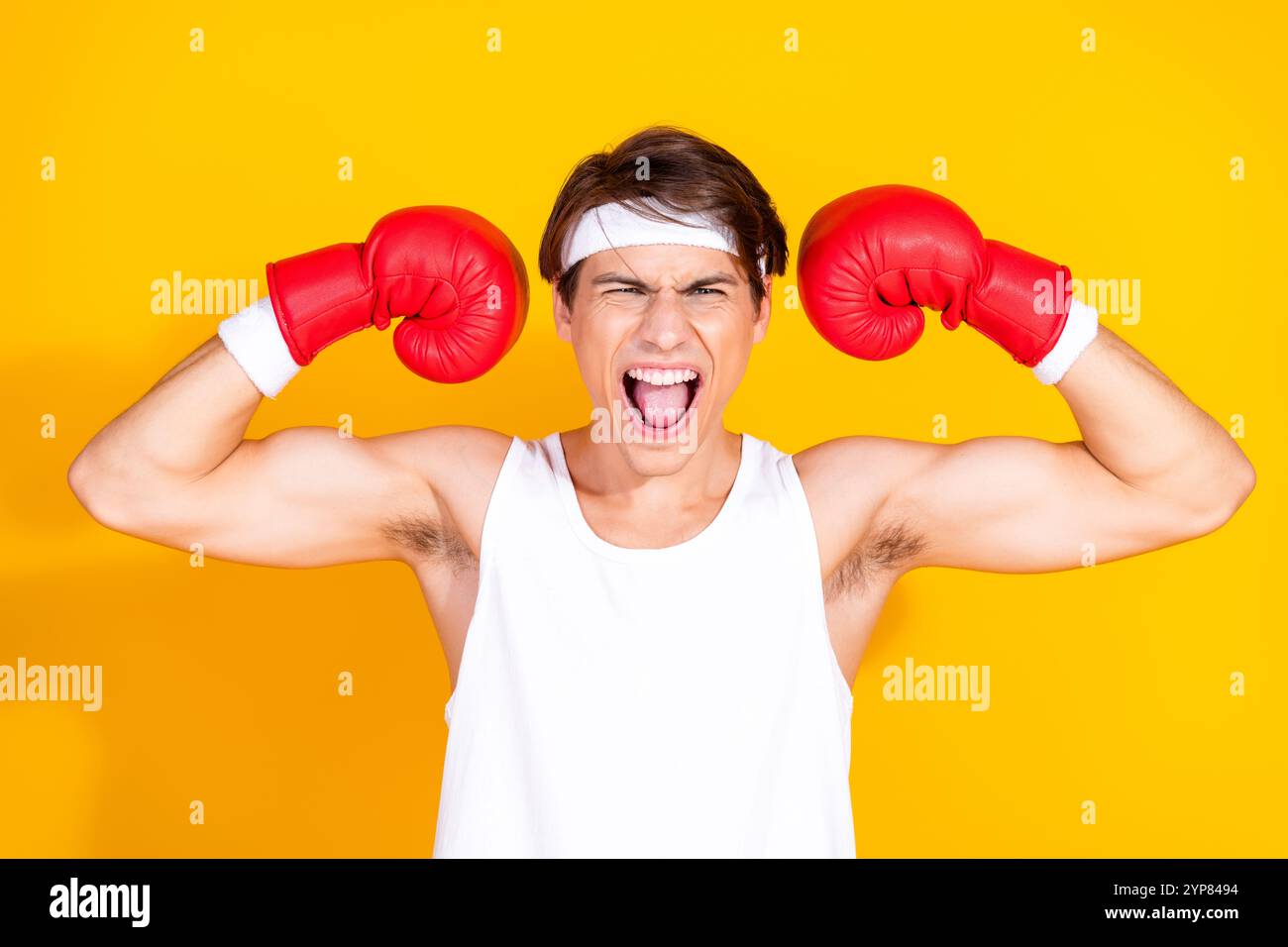 Energetic young man in boxing pose against vibrant yellow background ...