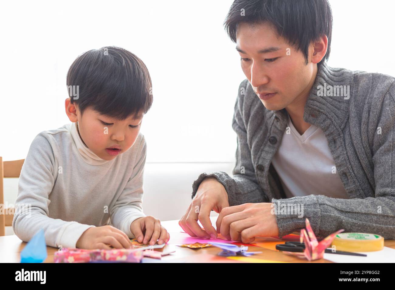 Parent and child doing Origami Stock Photo - Alamy