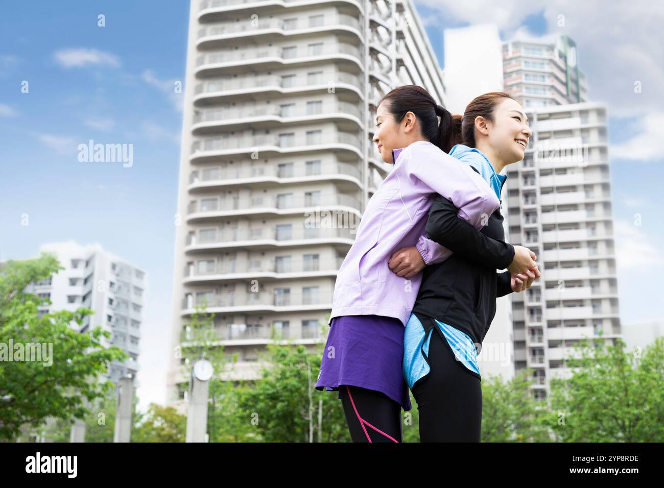 Two women standing back-to-back Stock Photo - Alamy