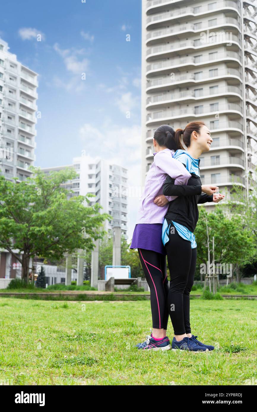 Two women standing back-to-back Stock Photo - Alamy
