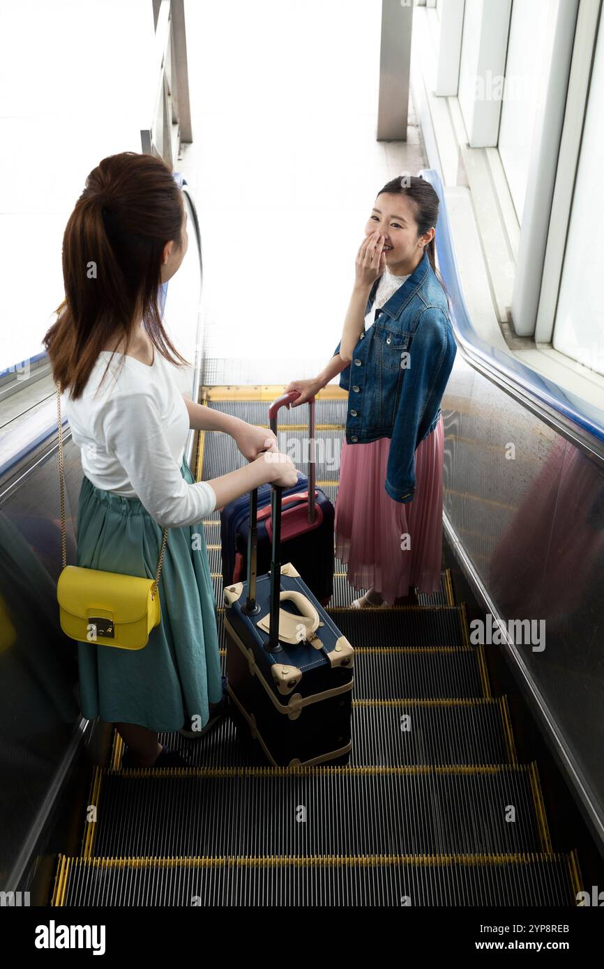Two women riding the escalator Stock Photo - Alamy