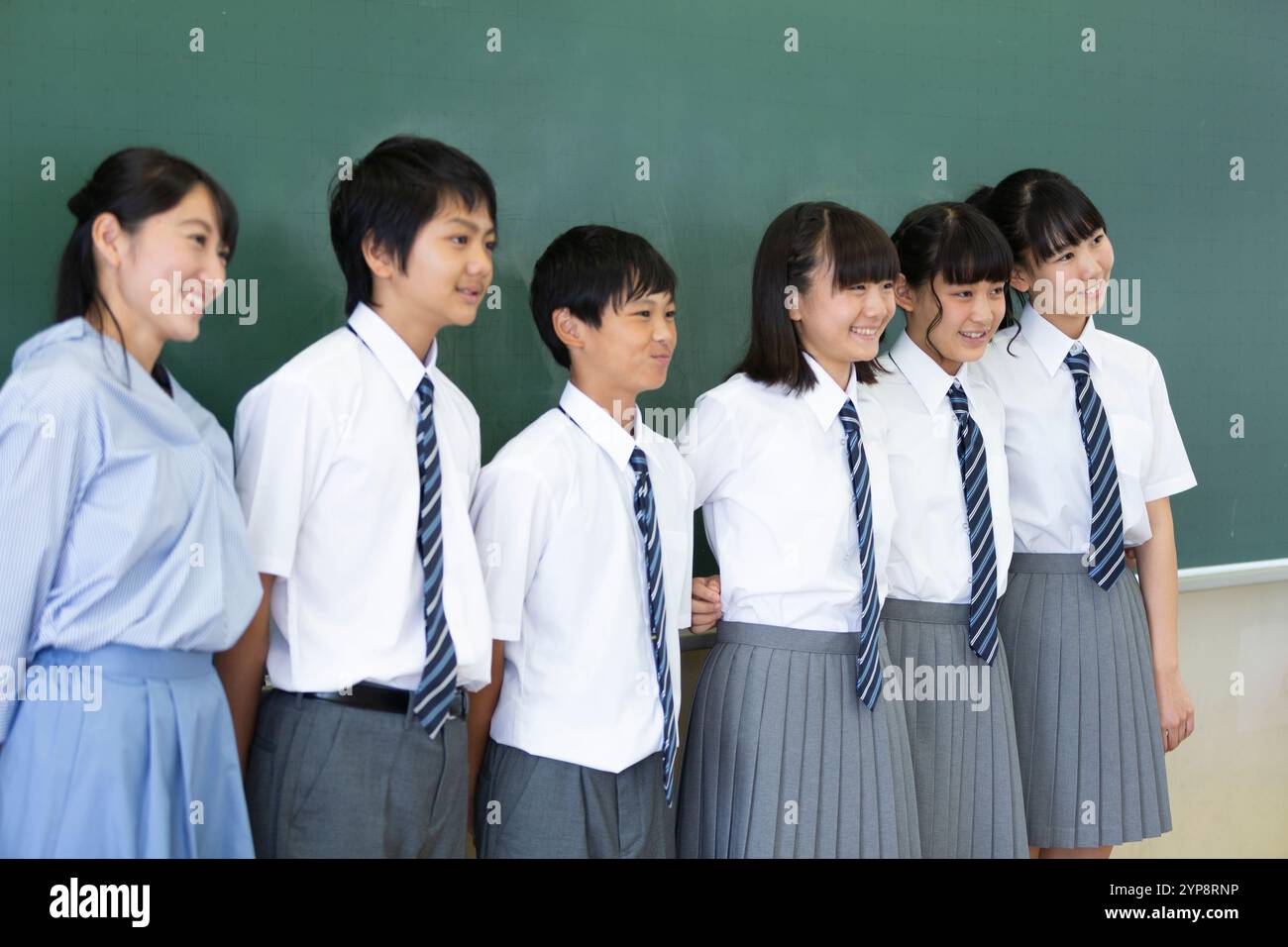 Junior high school students and teacher lined up in front of blackboard ...
