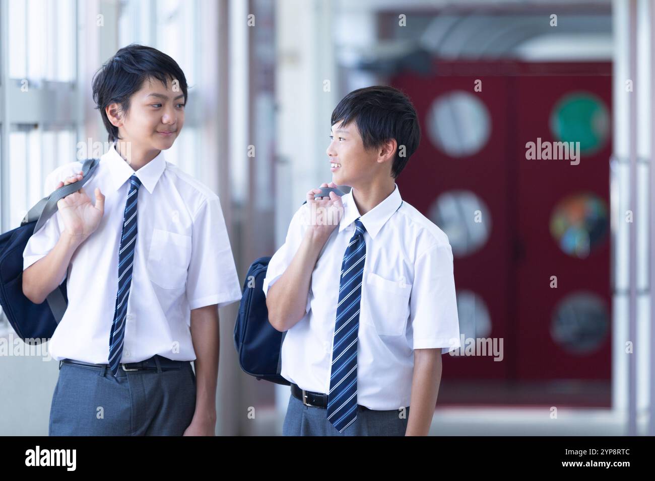 Junior high school students walking side by side down corridor Stock ...