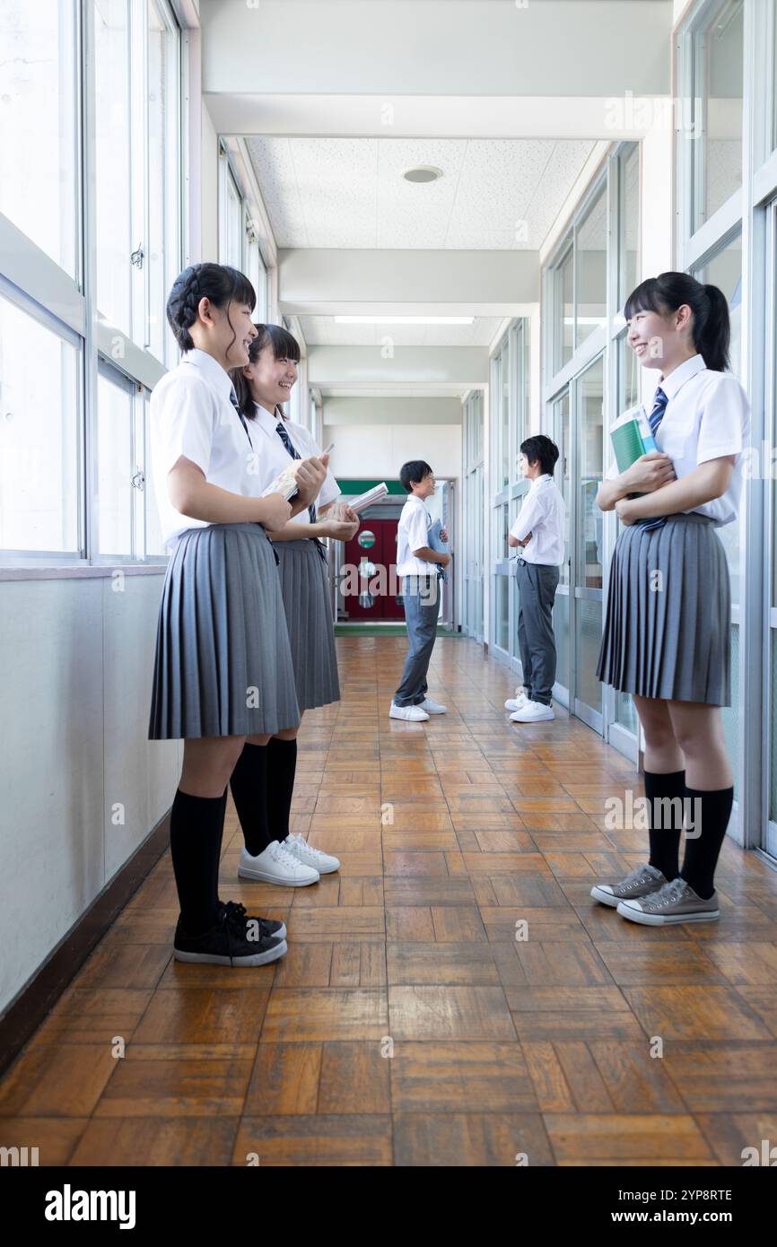 Junior high school students chatting in the corridor Stock Photo - Alamy