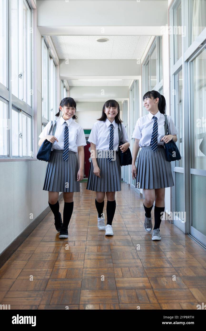 Junior high school students walking side by side down corridor Stock ...