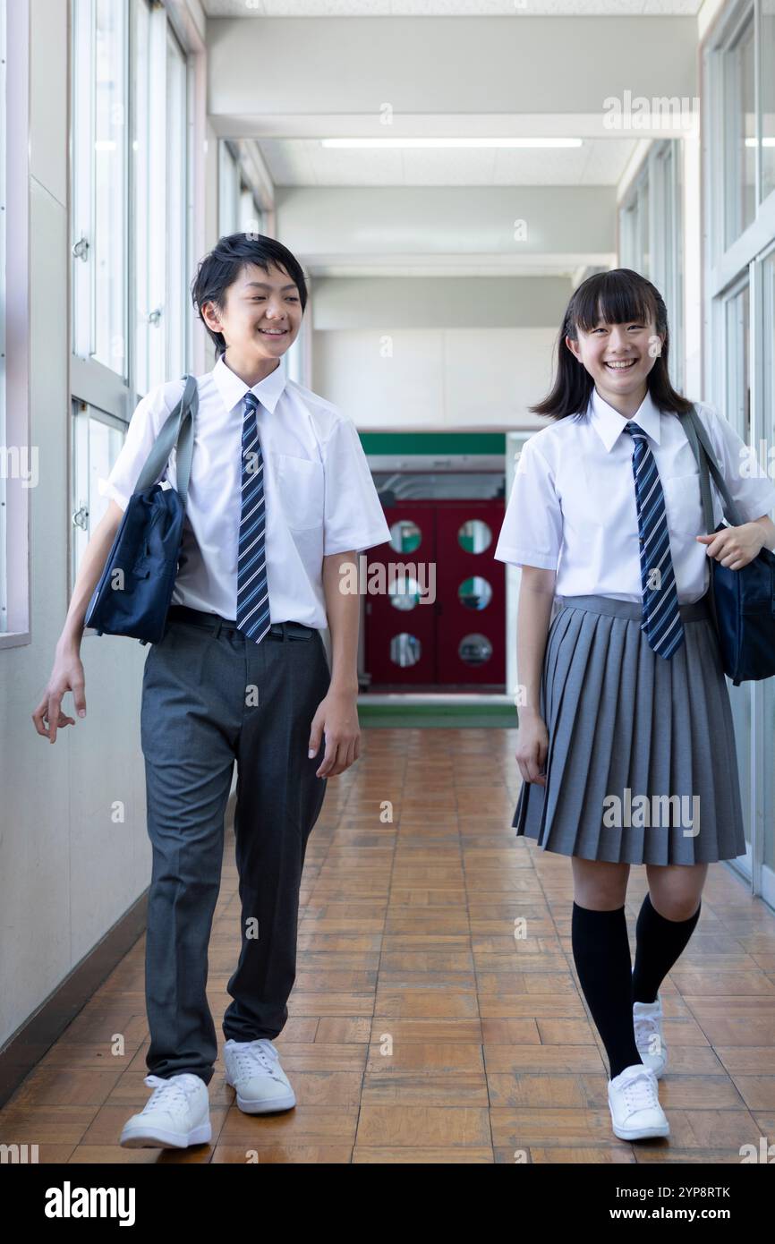 Junior high school students walking side by side down corridor Stock ...
