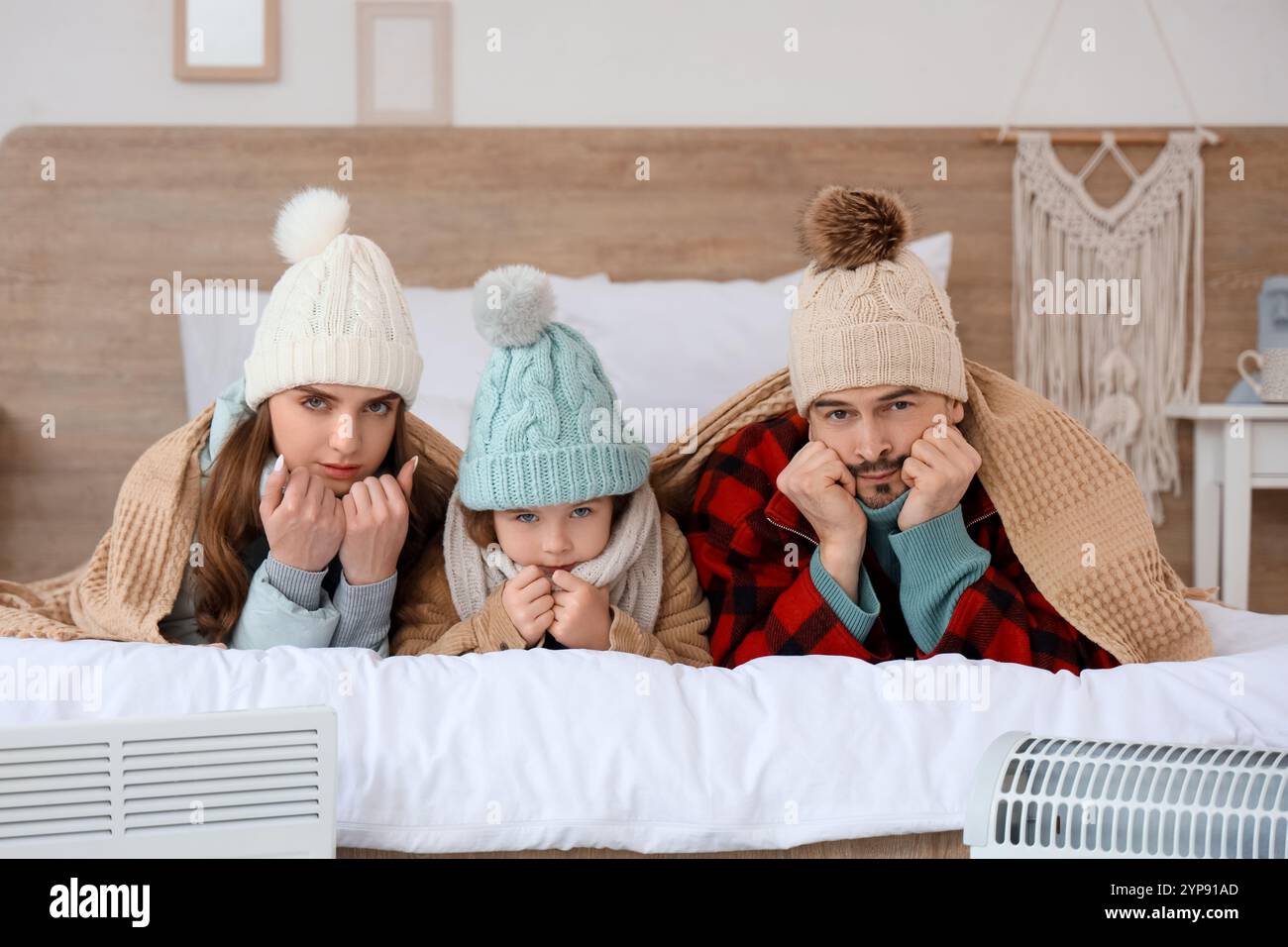 Frozen family lying near electric convector heaters in bedroom Stock ...
