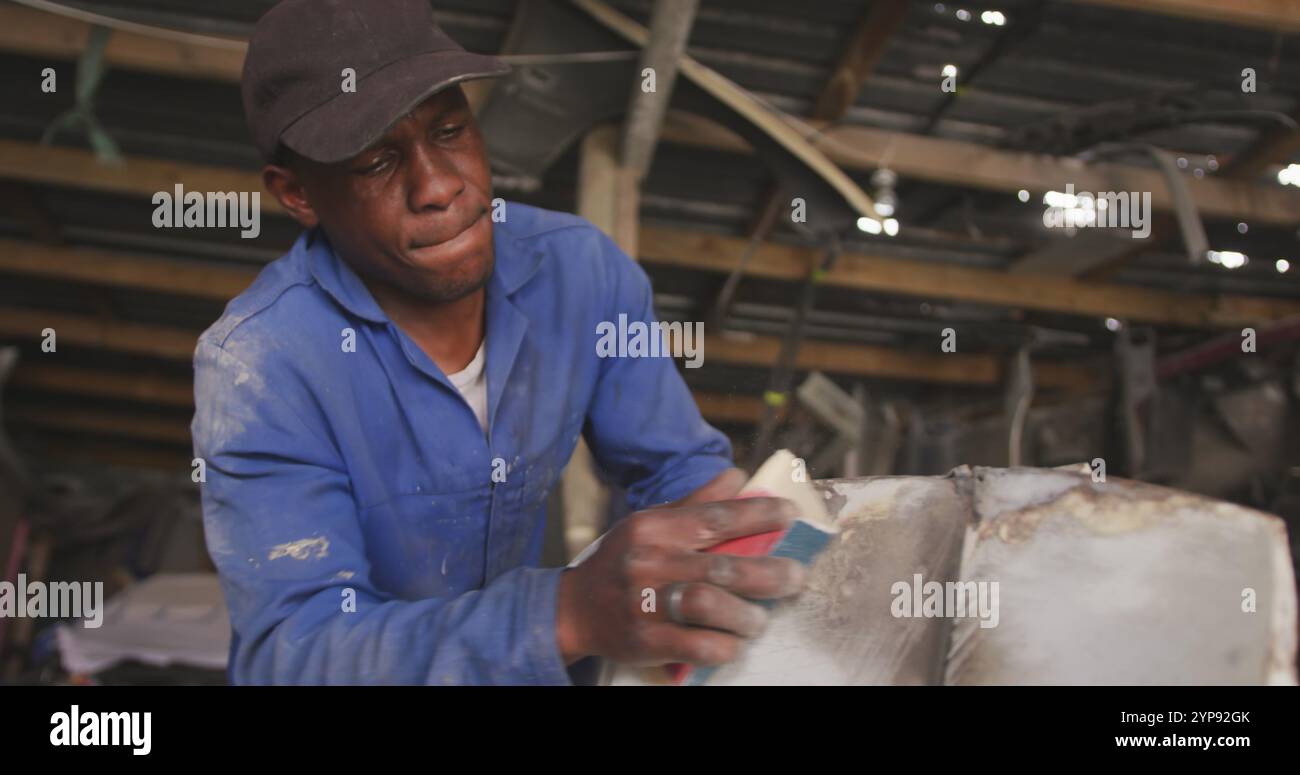 Front view of an African male panel beater in a township workshop ...