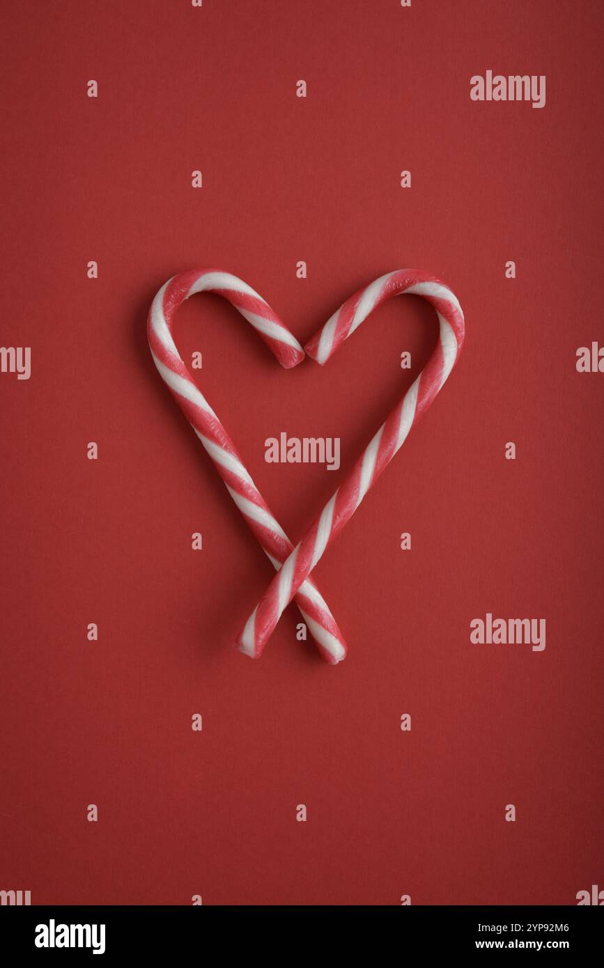 Christmas candy canes heart-shaped on red background, top view Stock ...