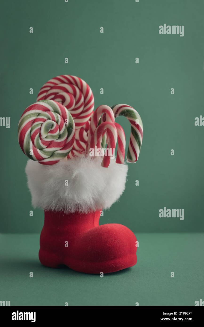 Christmas candy canes and lollipops in Santa Claus boot on green ...