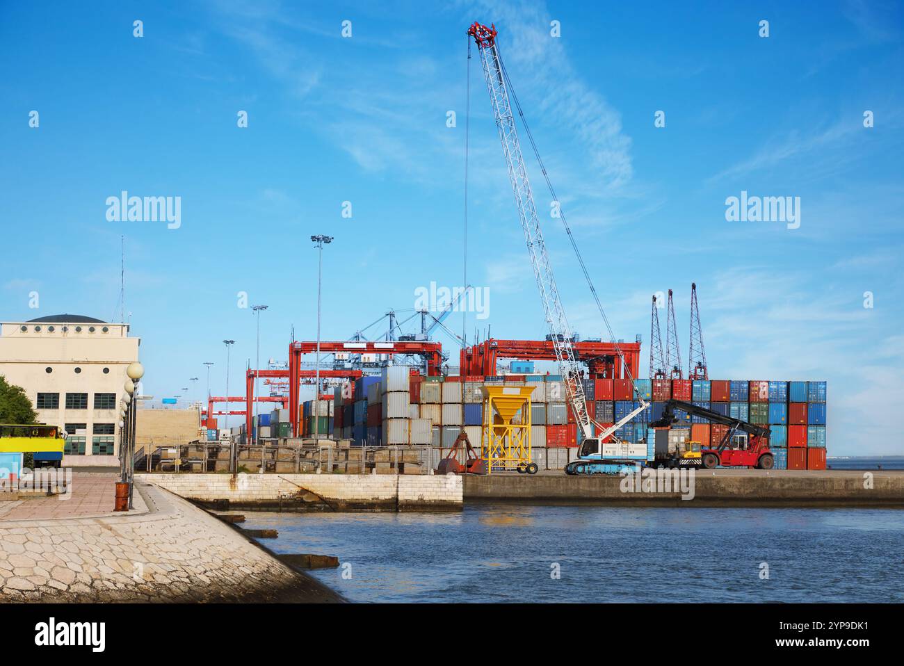 The forklift lifting and moving a large cargo container at a busy ...