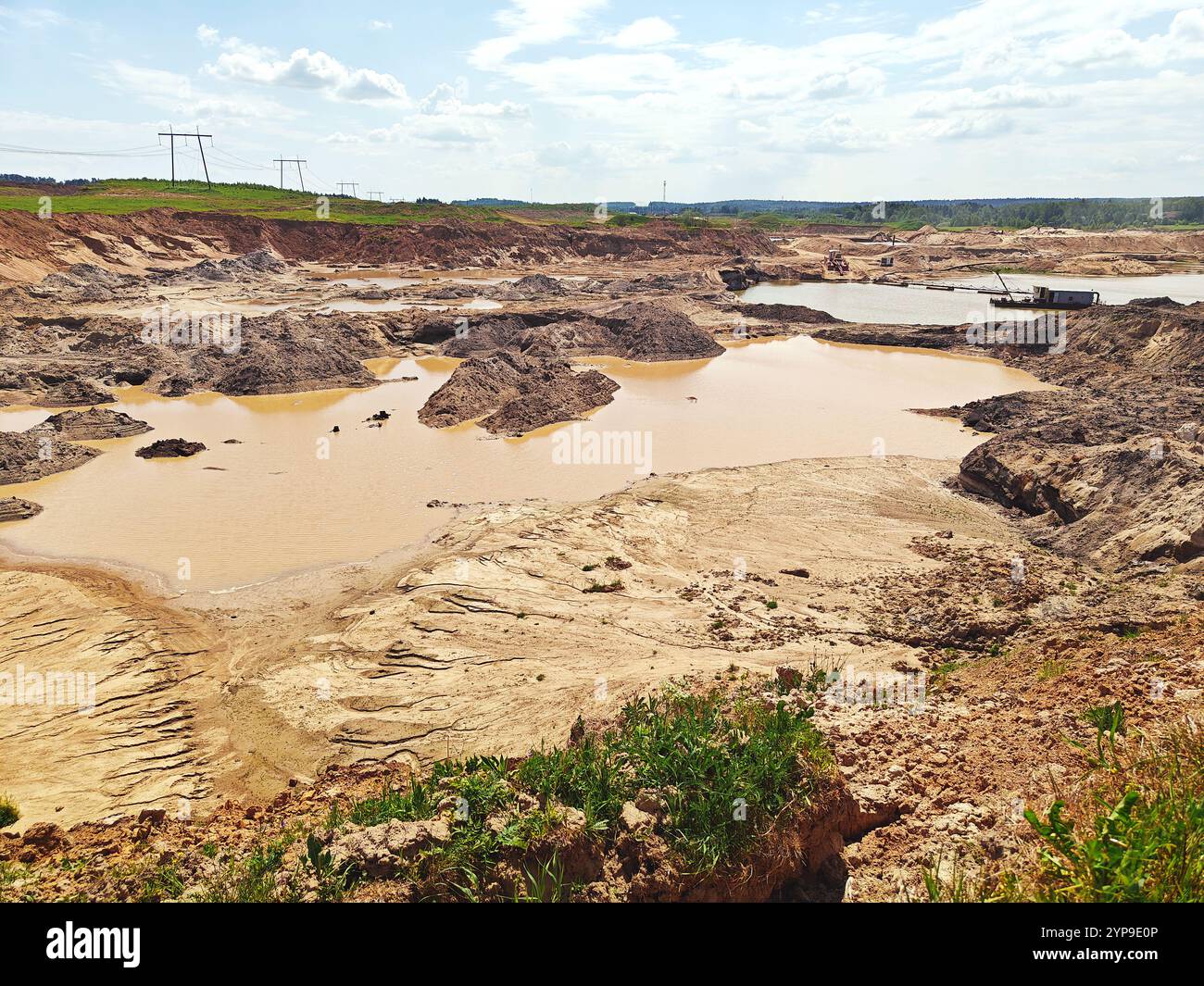Large excavation area features muddy water pools and rocky terrain ...
