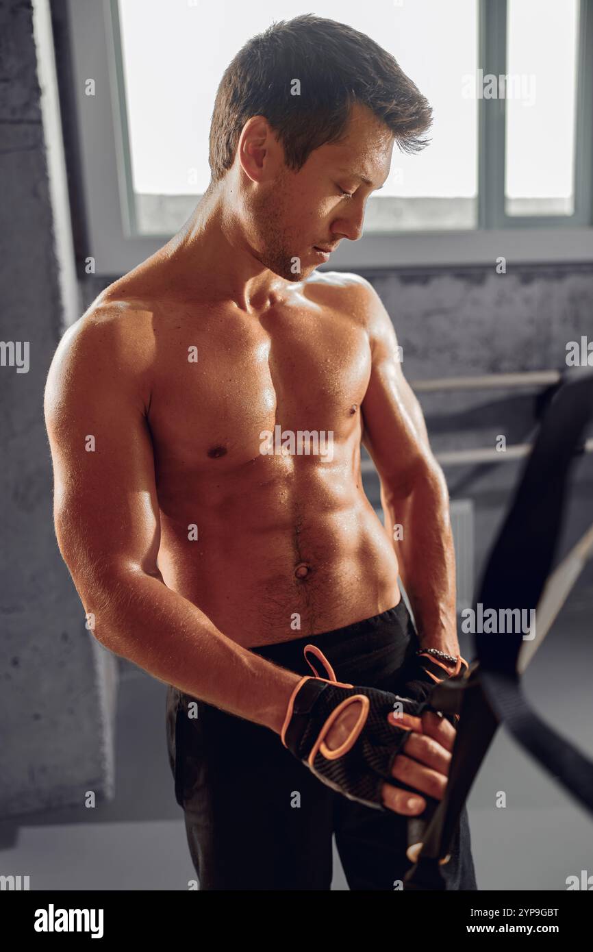 A fit man is training hard in the gym with intense focus and unwavering ...