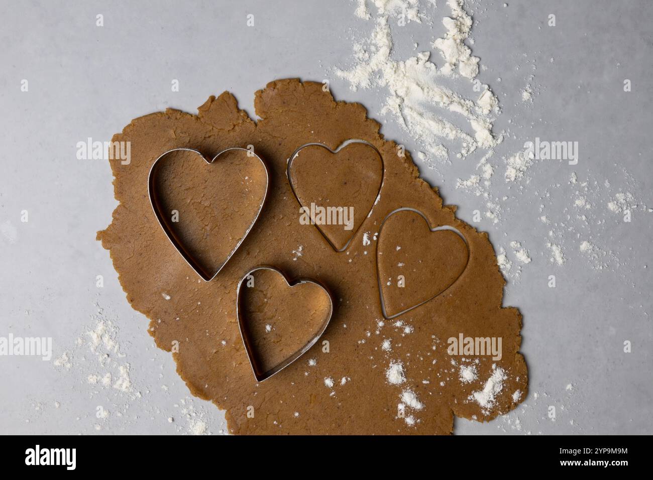 Cookie dough is rolled out with heart-shaped cutters ready for baking ...