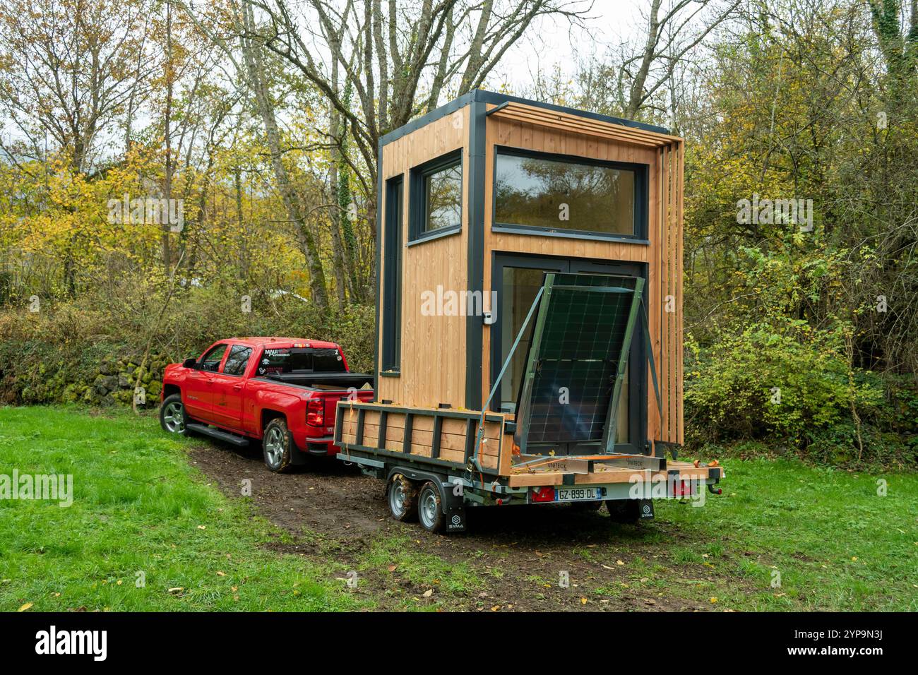 Modern tiny home (Homnest company) on wheels towed by a red truck in a ...