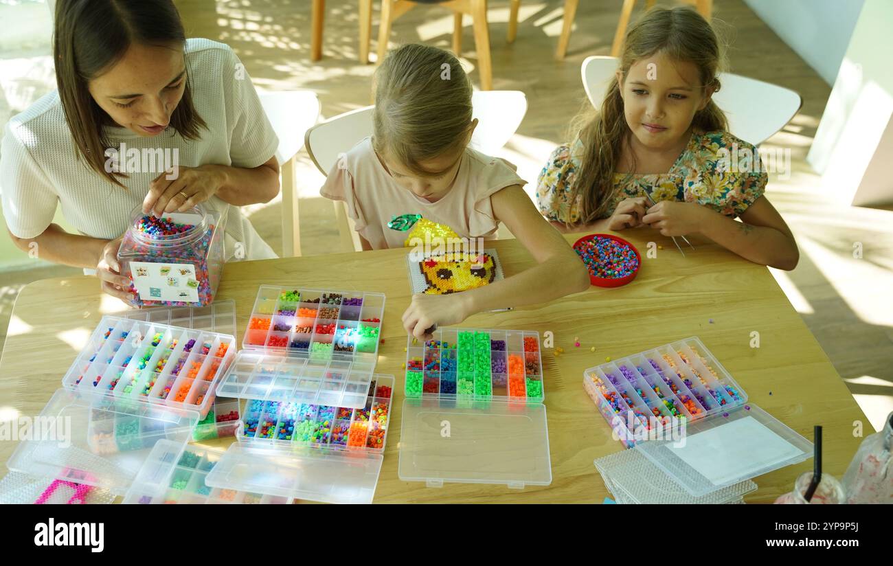 Teacher in workshop teched two girls how to assemble a thermo mosaic ...