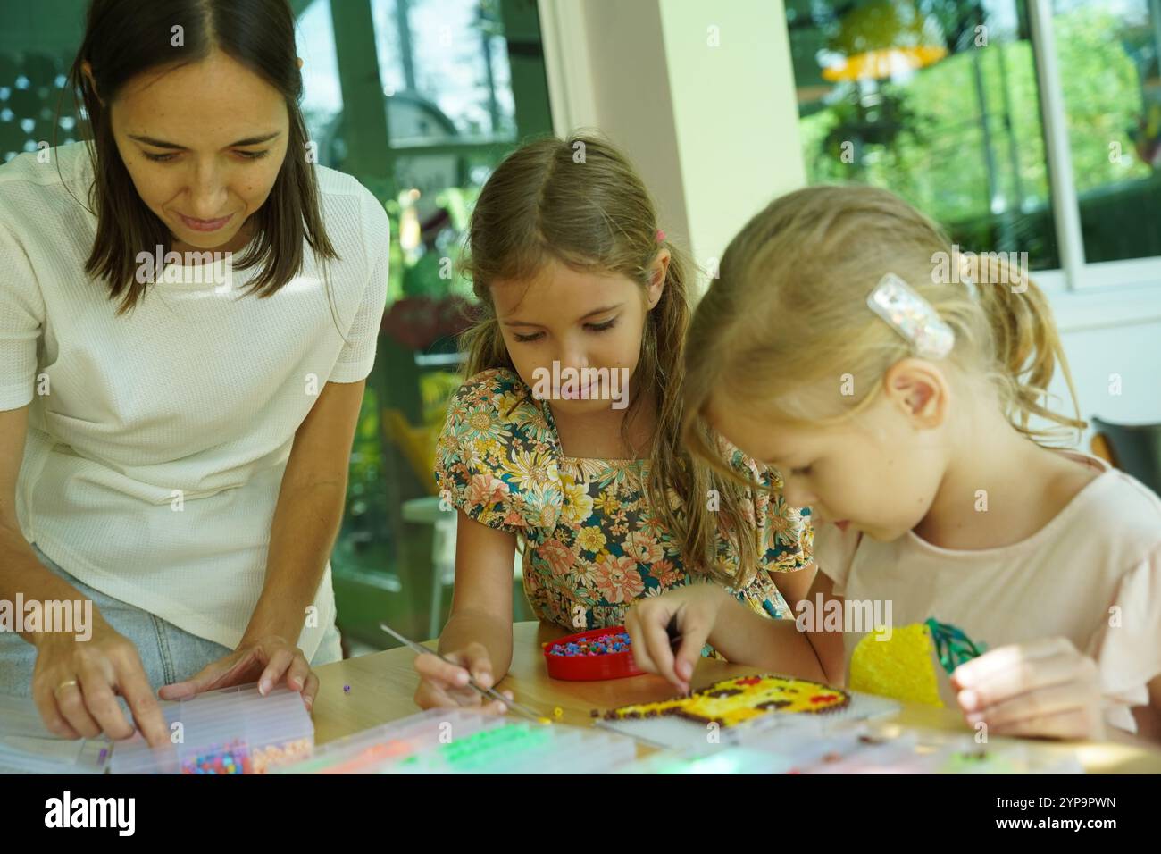 Teacher in workshop teched two girls how to assemble a thermo mosaic ...