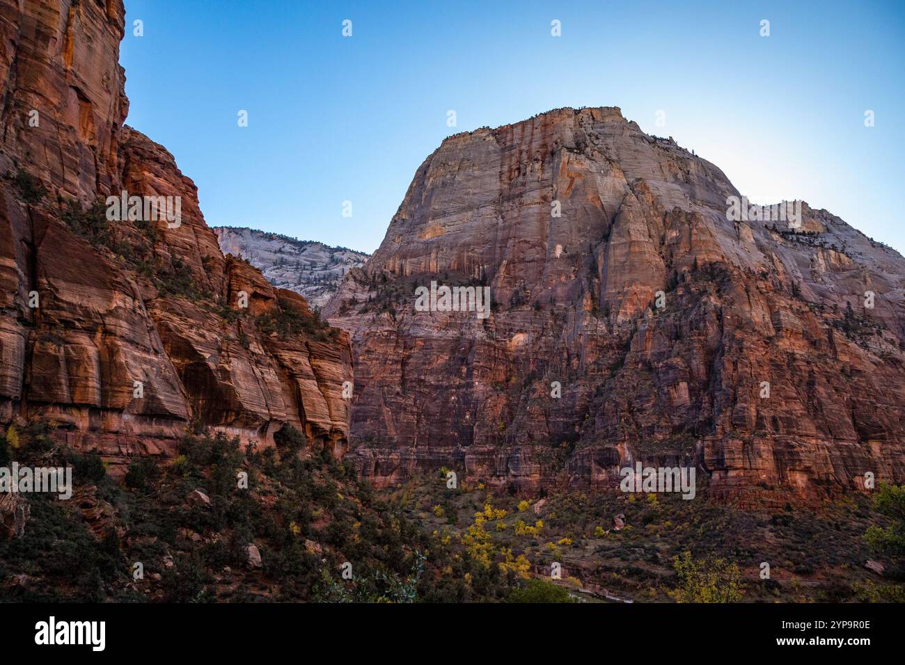 Towering sandstone cliffs catch the warm light of a Utah sunset ...