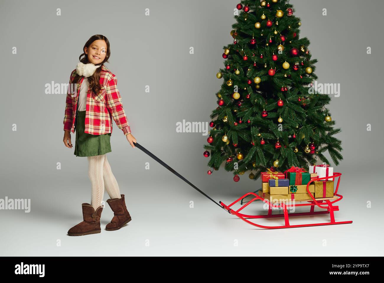 Happy girl wearing cozy attire drags a colorful sleigh filled with ...