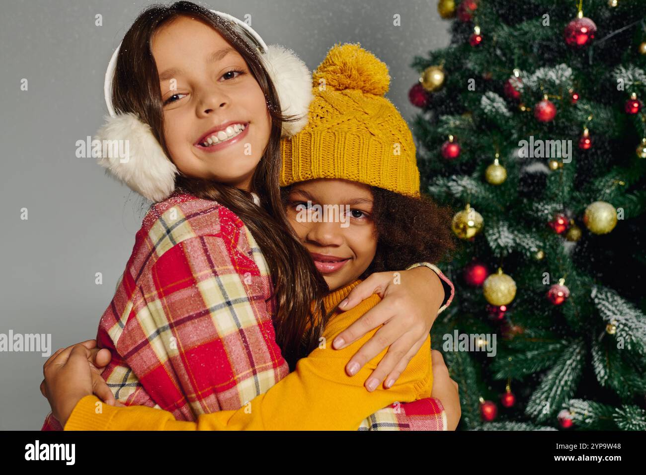 Two happy girls in colorful winter clothes joyfully embrace and ...