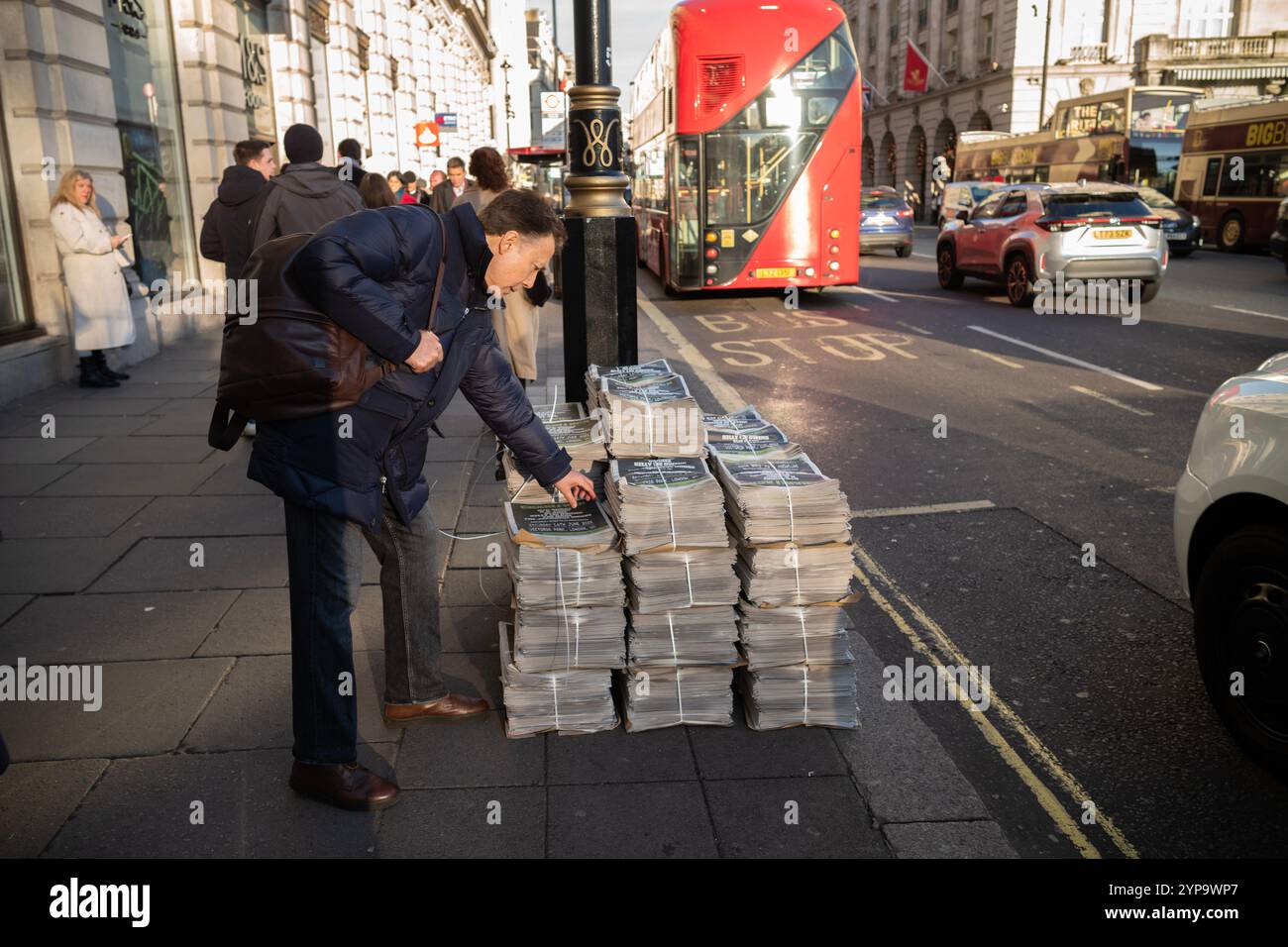 Stacks of evening newspapers stand on the street along Piccadilly ...