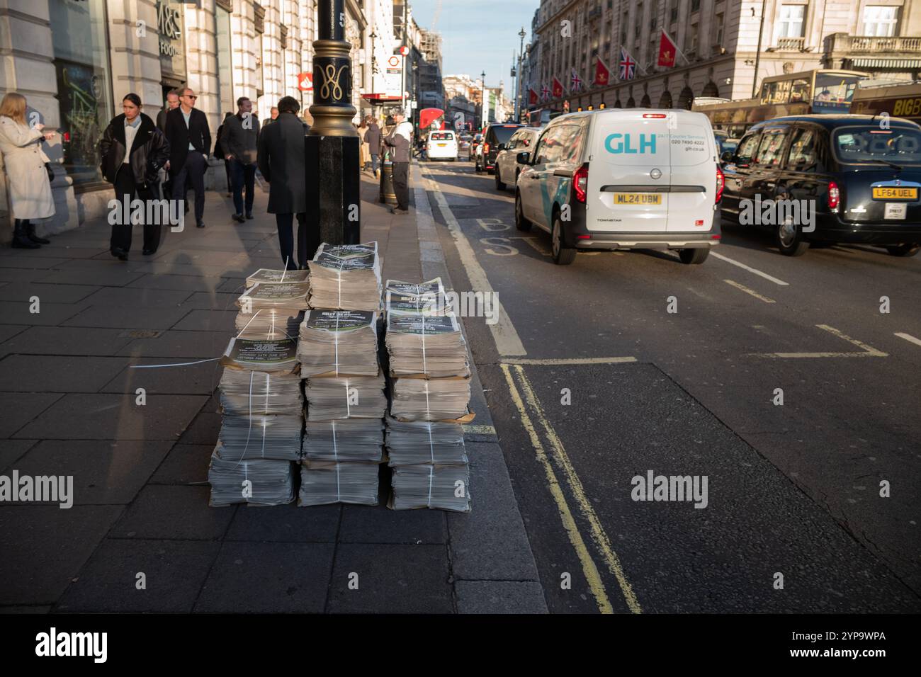 Stacks of evening newspapers stand on the street along Piccadilly ...