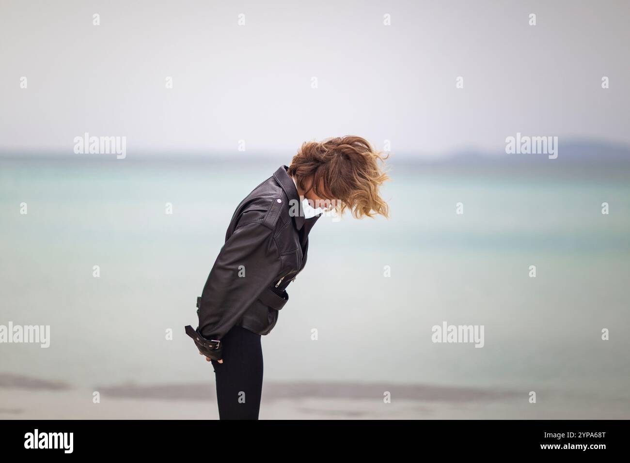 Woman in black leather jacket leaning forward by the sea hi-res stock ...