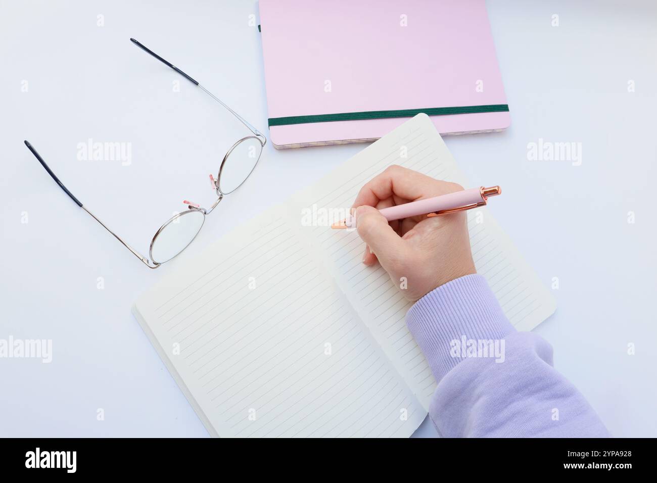 Minimalist writing setup: hands, pink accessories, and glasses Stock ...