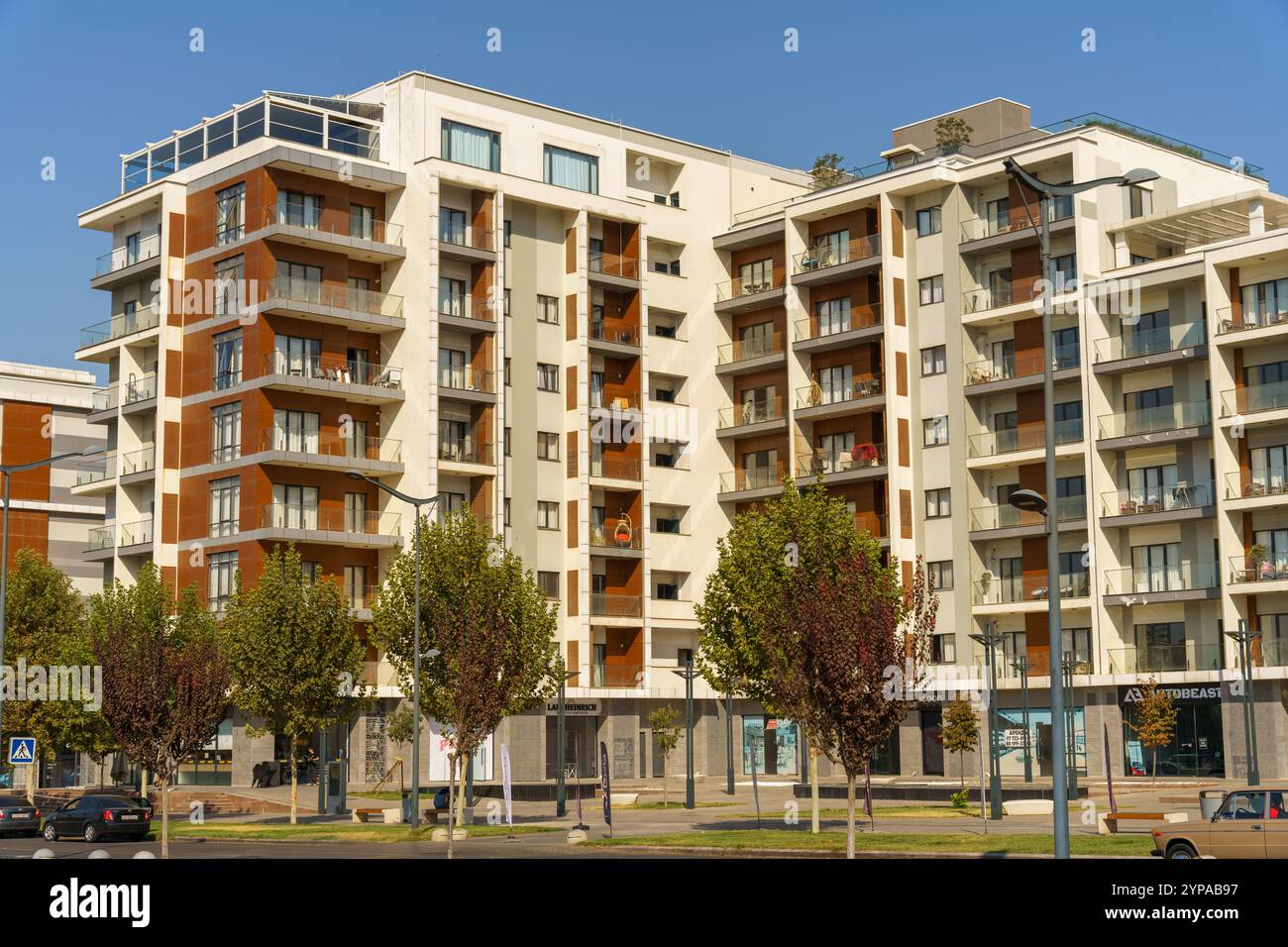 A large apartment building with a green tree in front of it Stock Photo ...