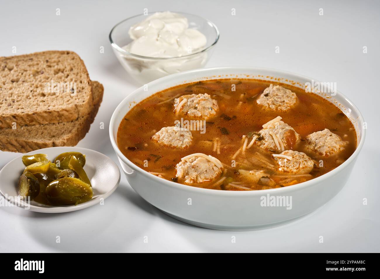 Meatball soup with bread, sour cream and pickled jalapeno, on white ...