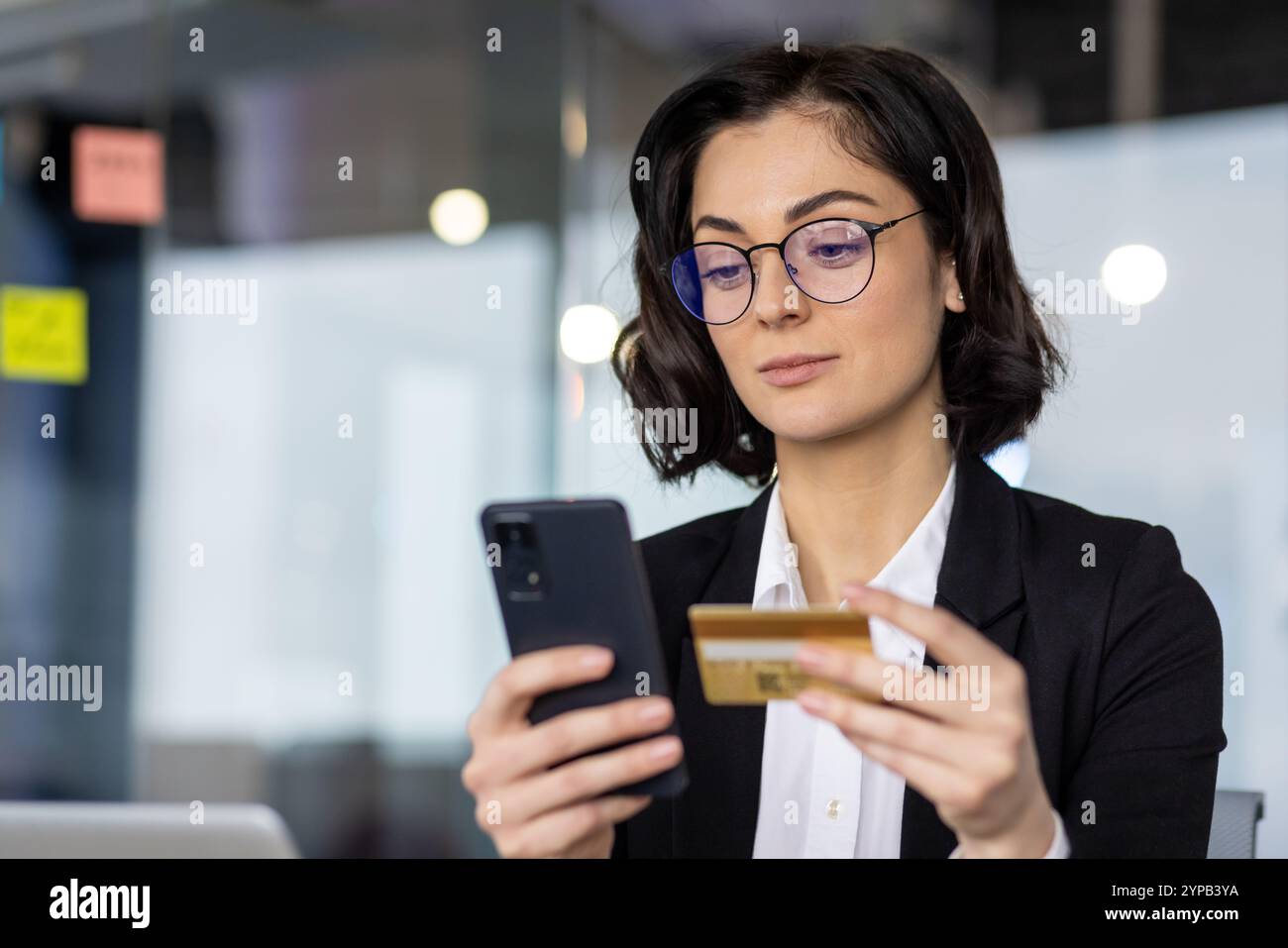 Woman in office making online payment using smartphone and credit card ...